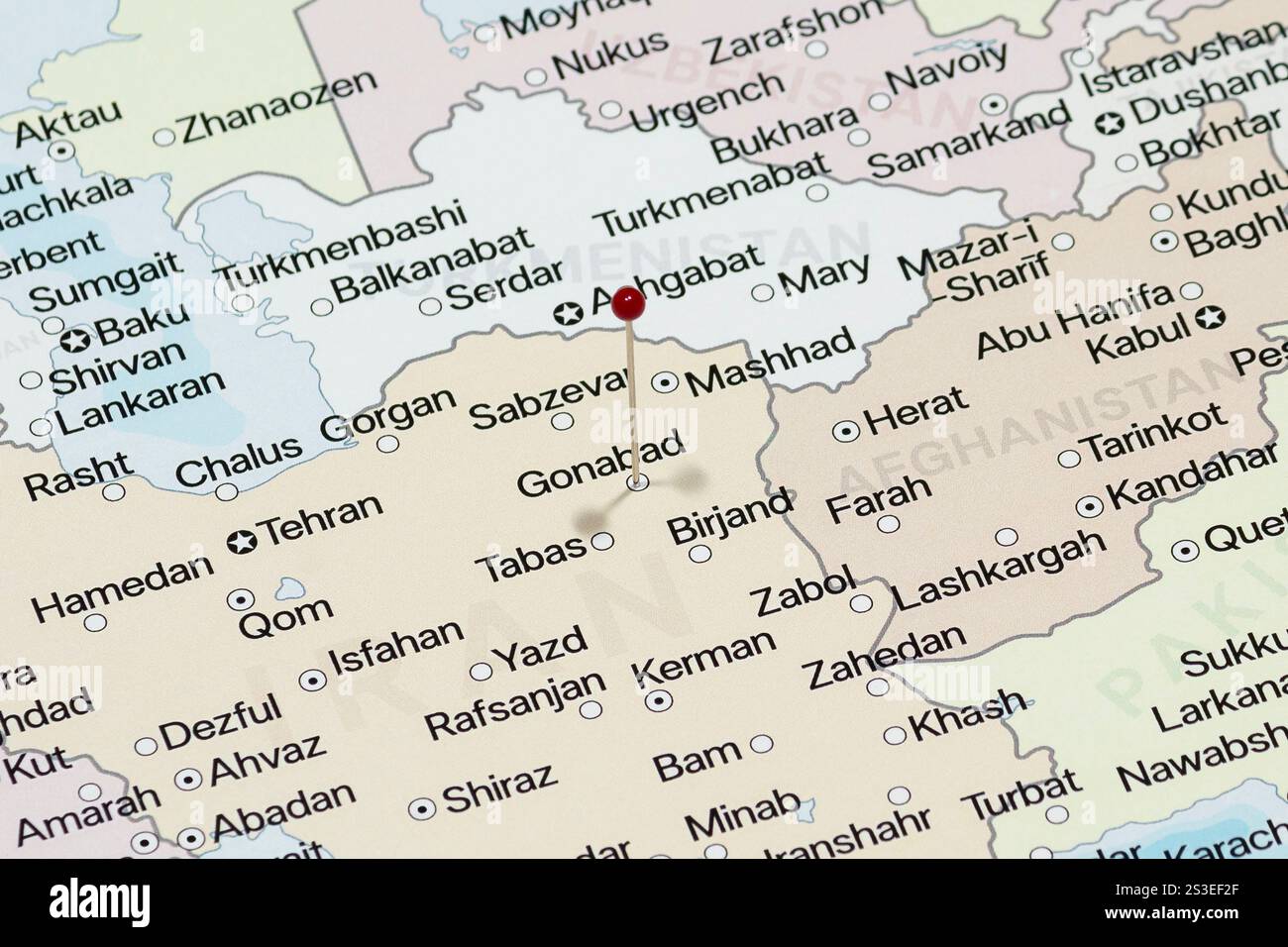 Macro photo of a red pin needle into Gonabad city of Iran political map ...