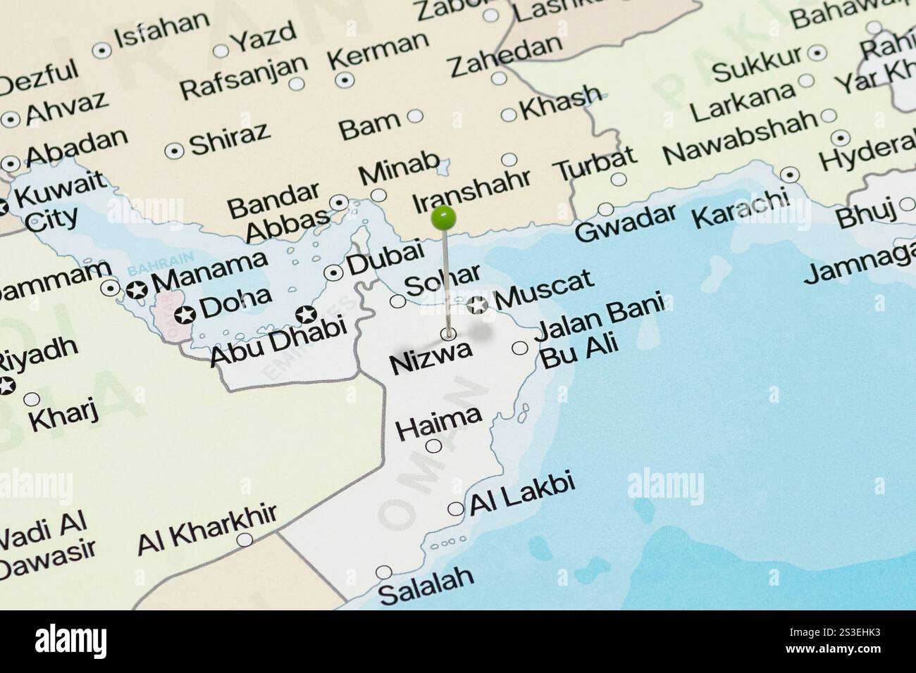 Macro photo of a green pin needle into Nizwa city of Oman political map ...