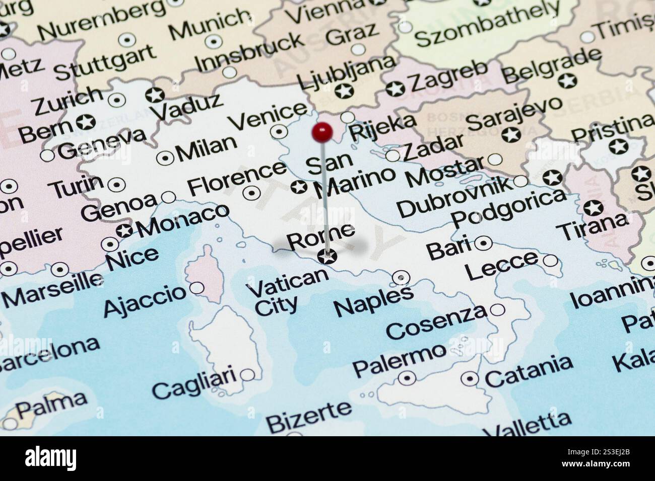 Macro photo of a red pin needle into Rome city of Italy political map ...