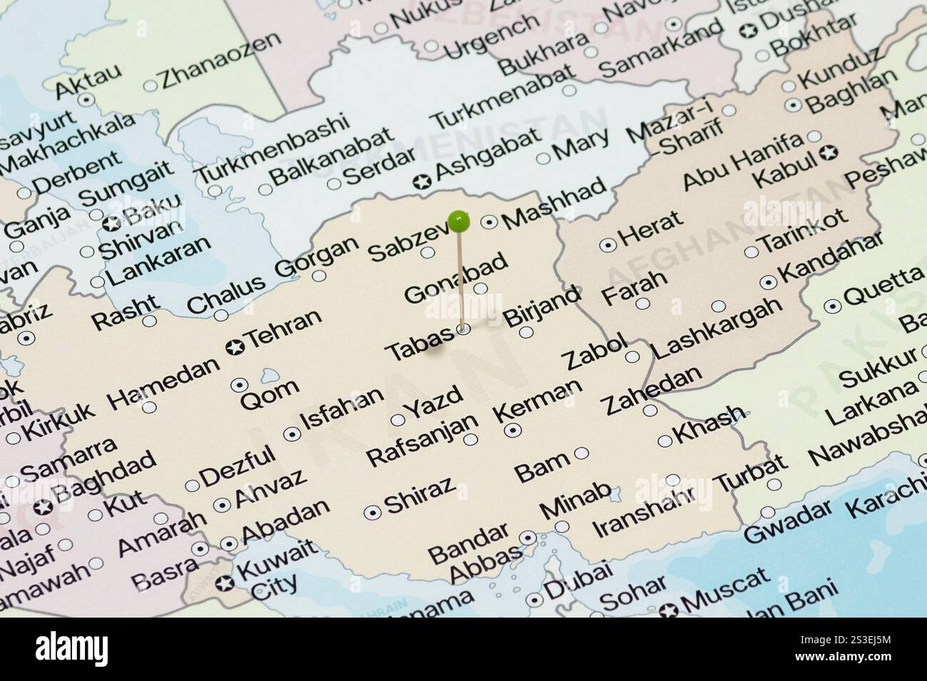 Macro photo of a green pin needle into Tabas city of Iran political map ...