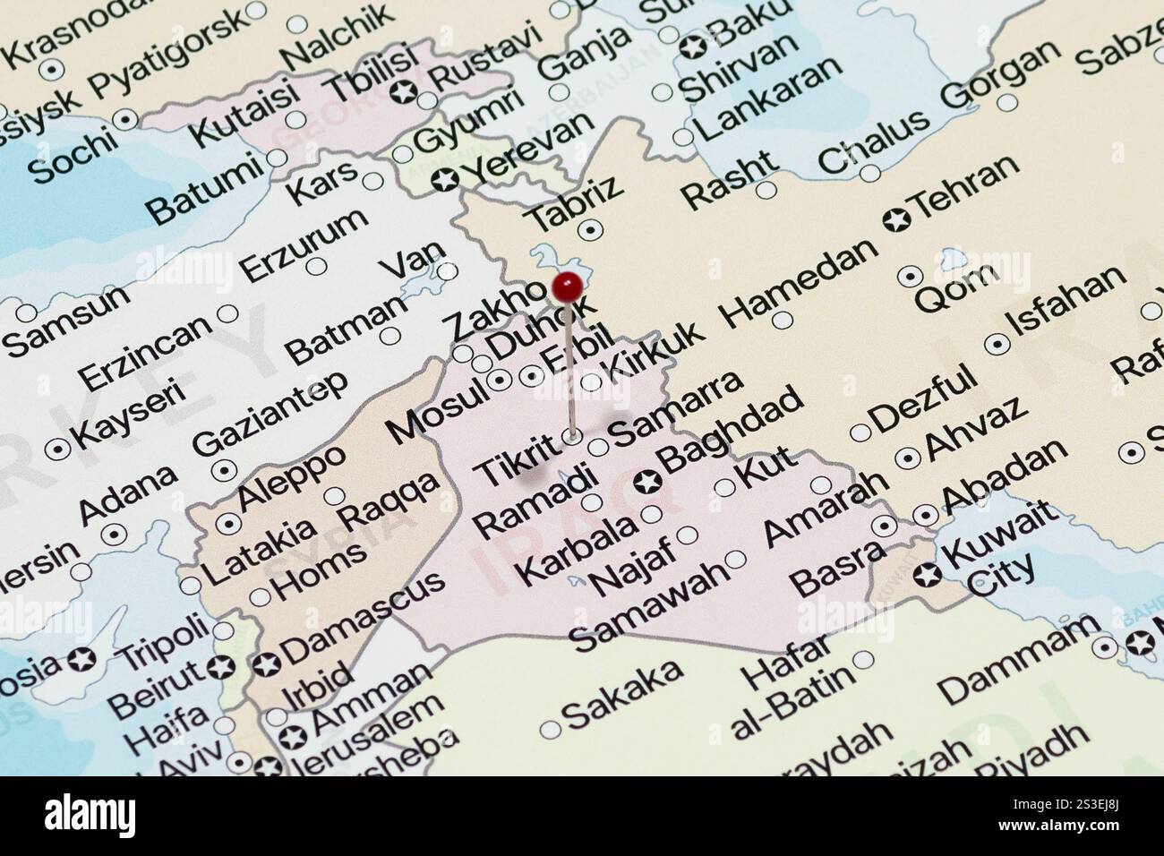 Macro photo of a red pin needle into Tikrit city of Iraq political map ...