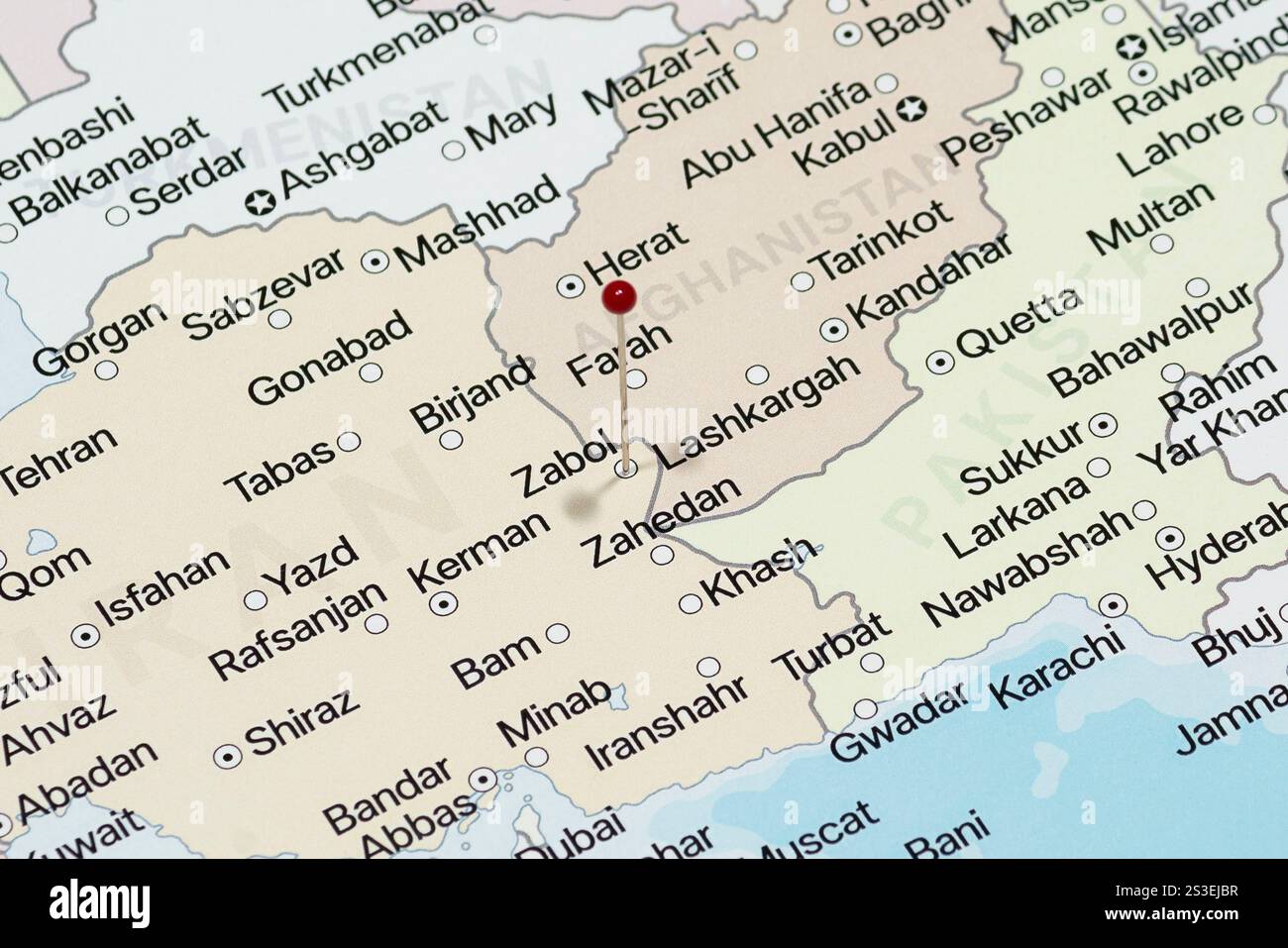 Macro photo of a red pin needle into Zabol city of Iran political map ...
