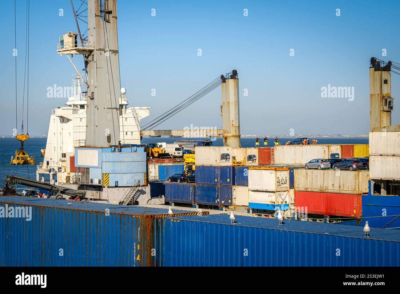 Cargo containers stacked with cars on top on bulk carrier in sea port ...
