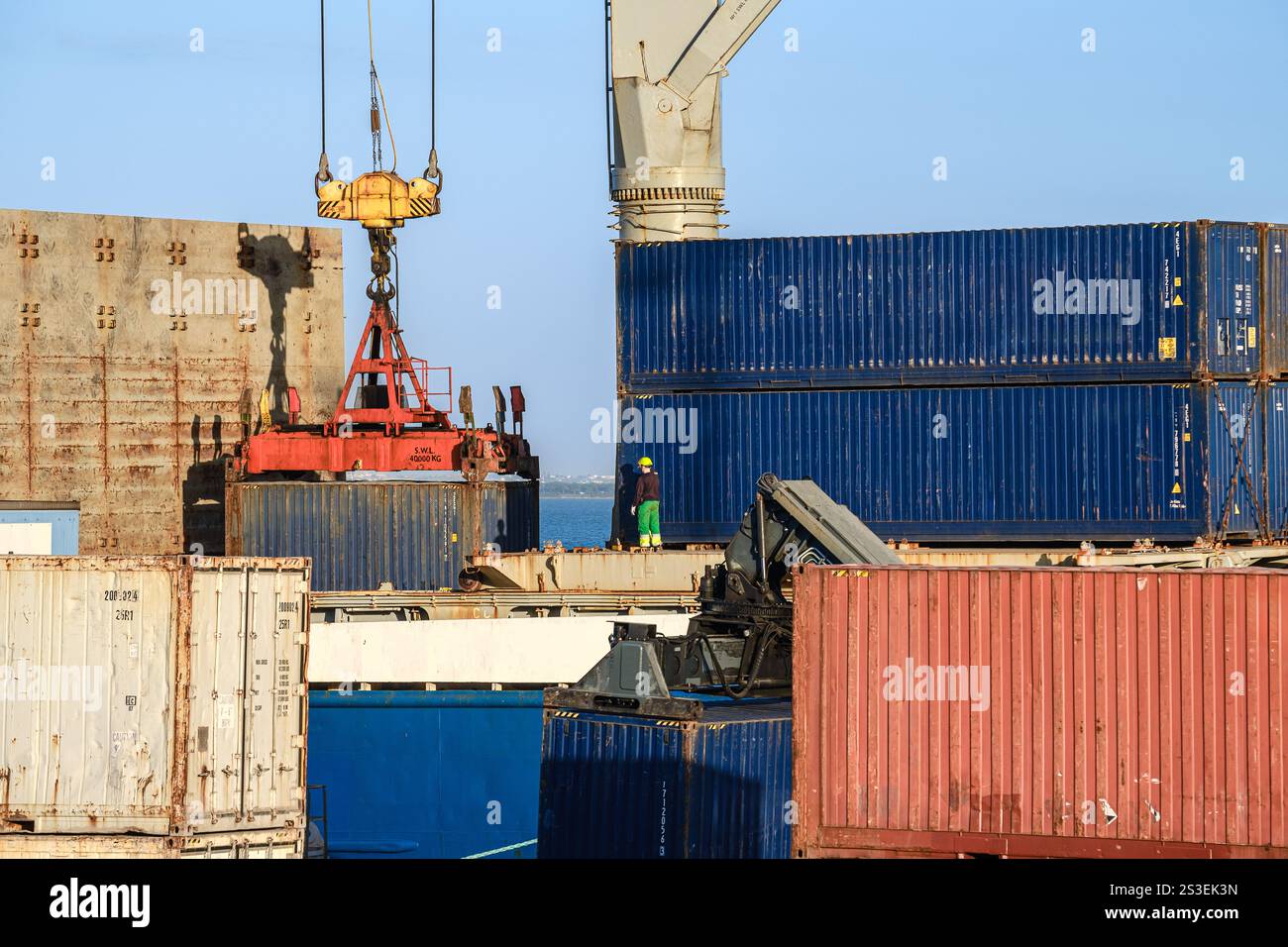 Sea port worker in safety gear supervises loading or unloading of cargo ...