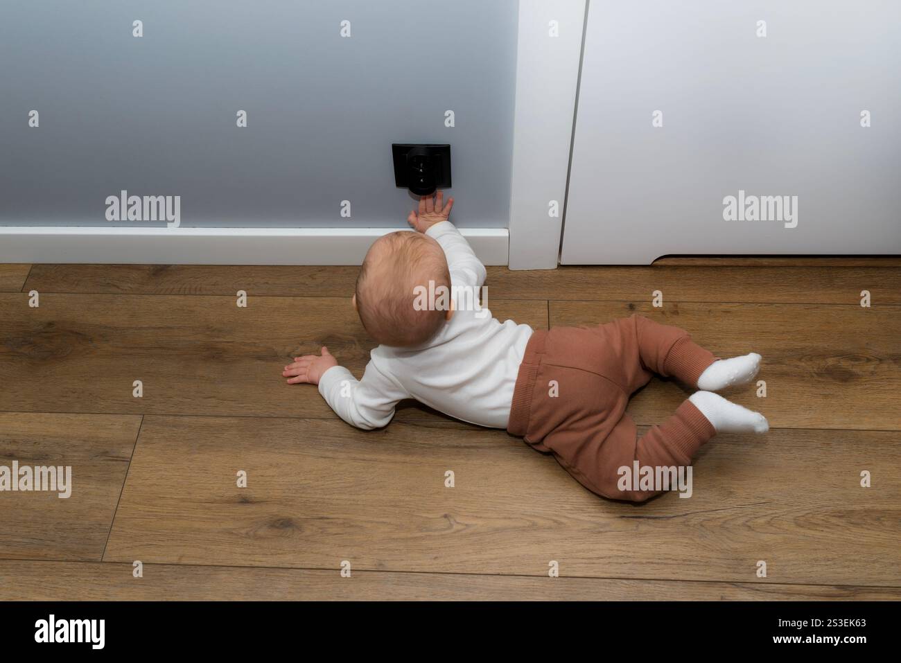 A seven-month-old Caucasian baby touches a black electrical outlet on ...
