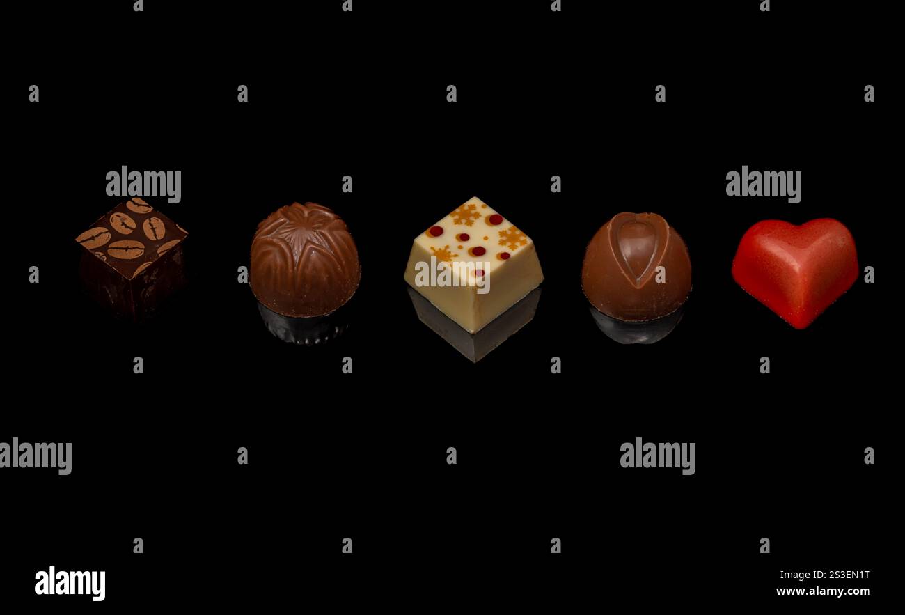 Set of five chocolate candy on black dark table Stock Photo - Alamy
