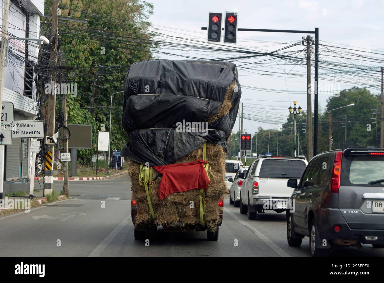 a heavily laden pick up truck carries bales of straw through the ...