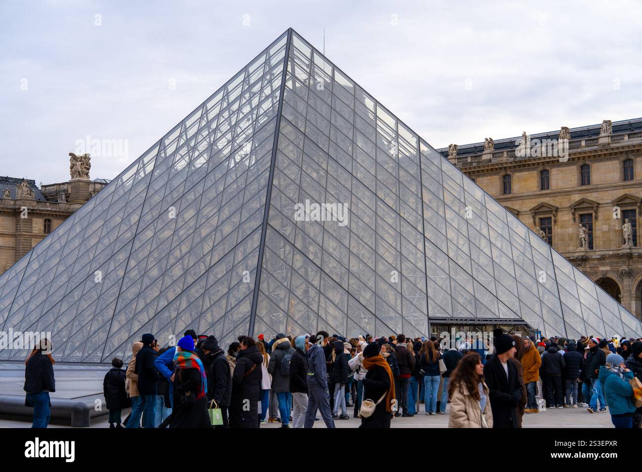 Visitors explore the iconic glass pyramid at Louvre Museum in Paris ...