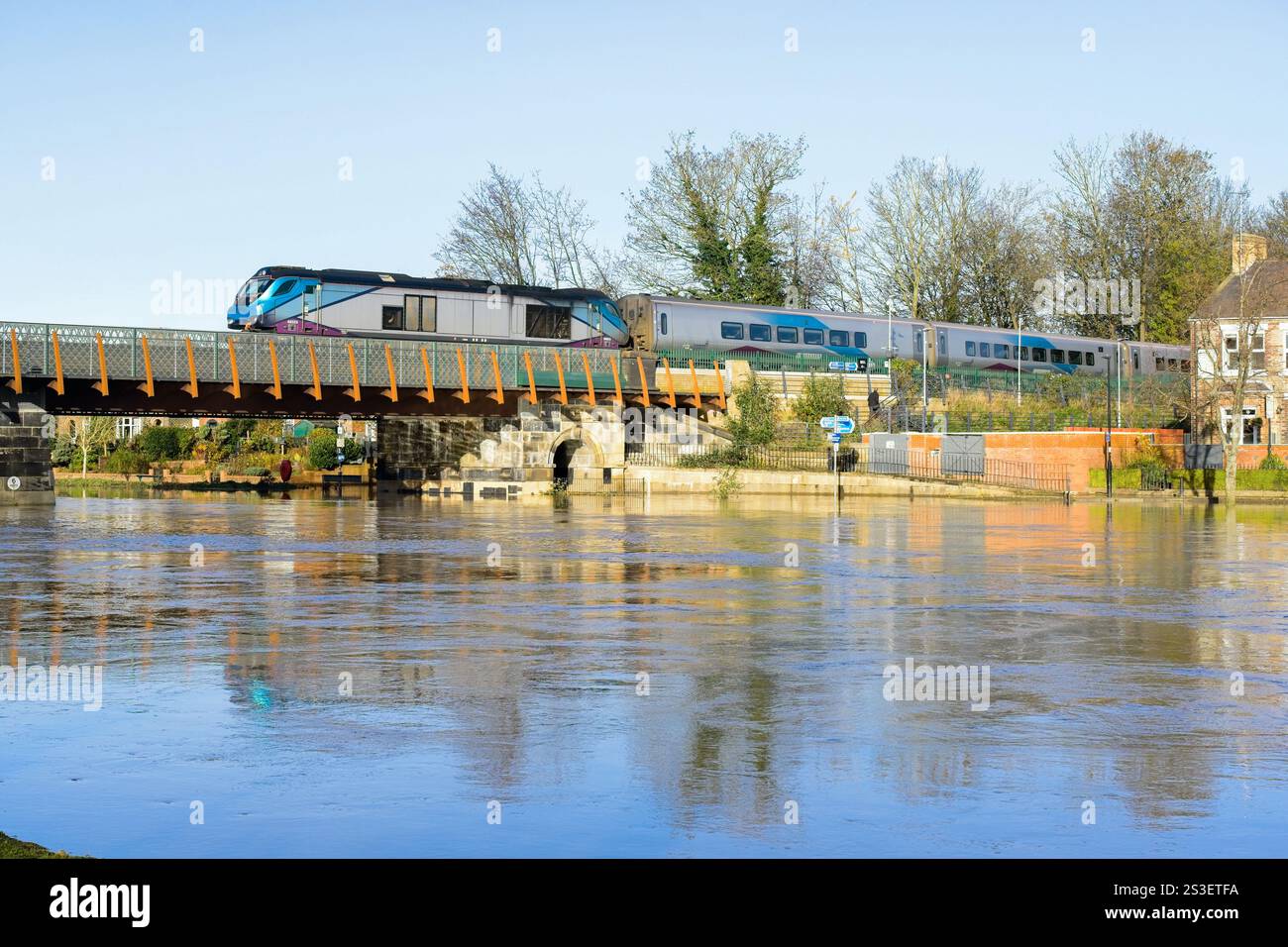 A passenger train crosses a bridge over a flooded River Ouse ...