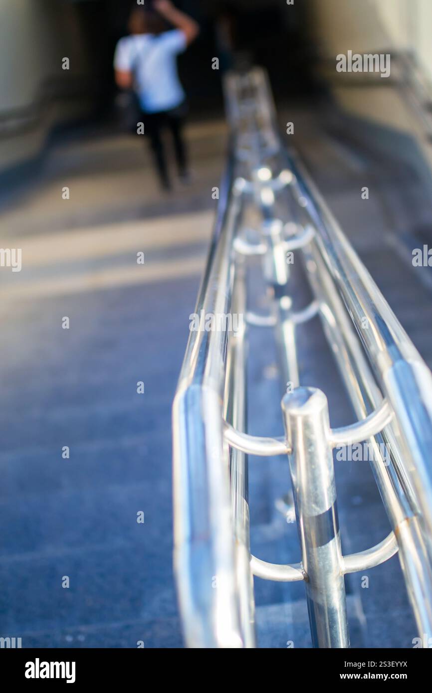 A person is walking down stairs using a metal railing for support Stock ...