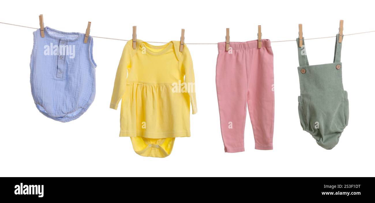 Different baby clothes drying on laundry line against white background ...