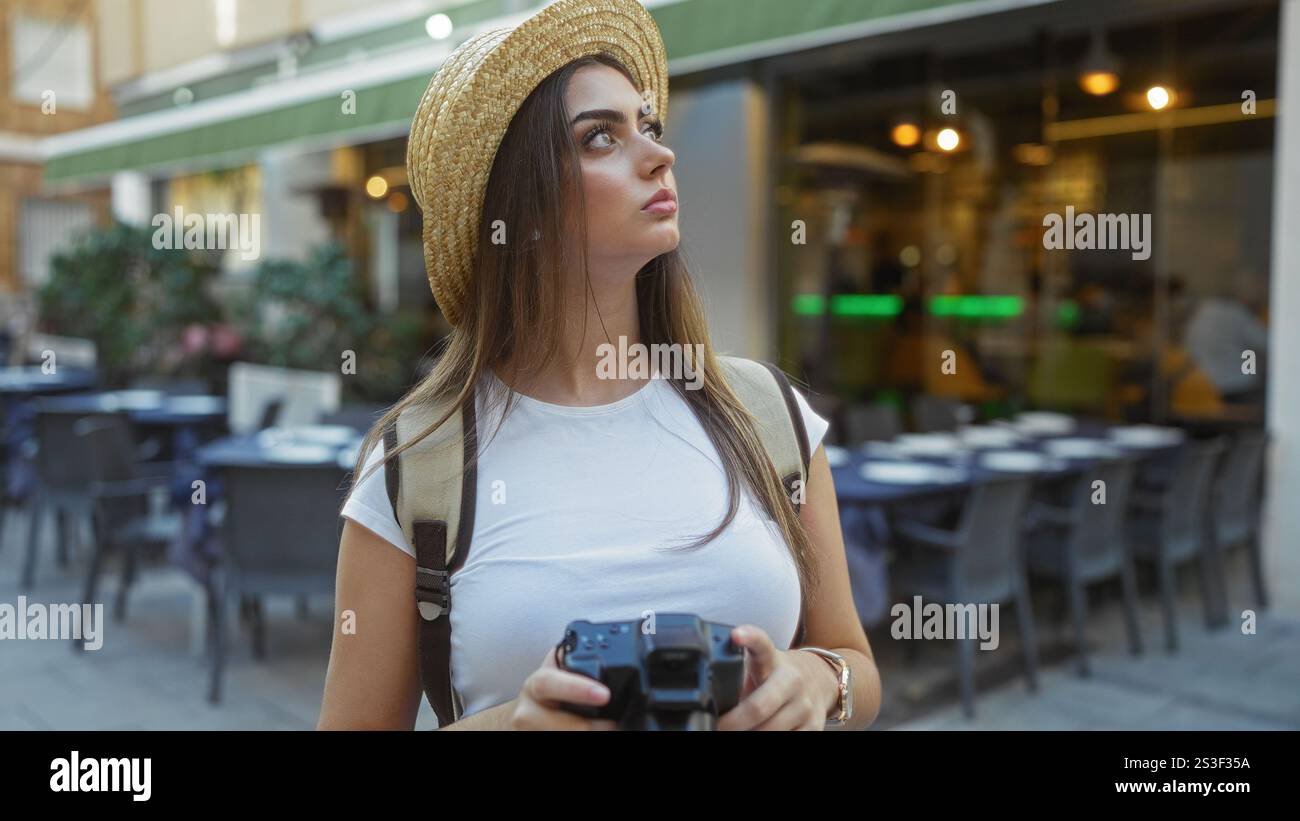 Woman with camera exploring outdoor urban cafe street wearing hat ...