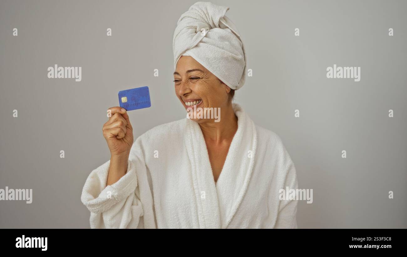 Mature woman in bathrobe holding credit card and smiling isolated on ...
