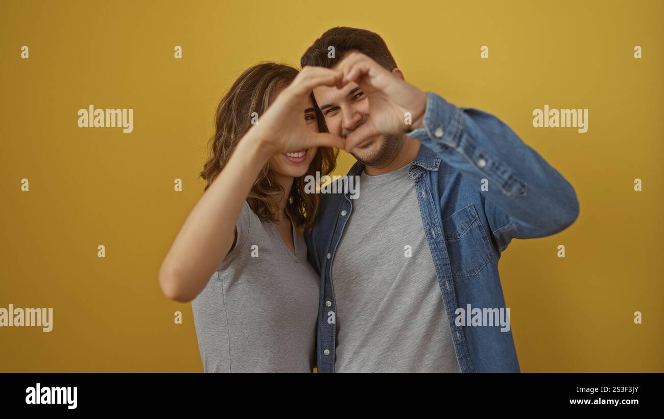 Man and woman forming a heart shape with their hands together against a ...