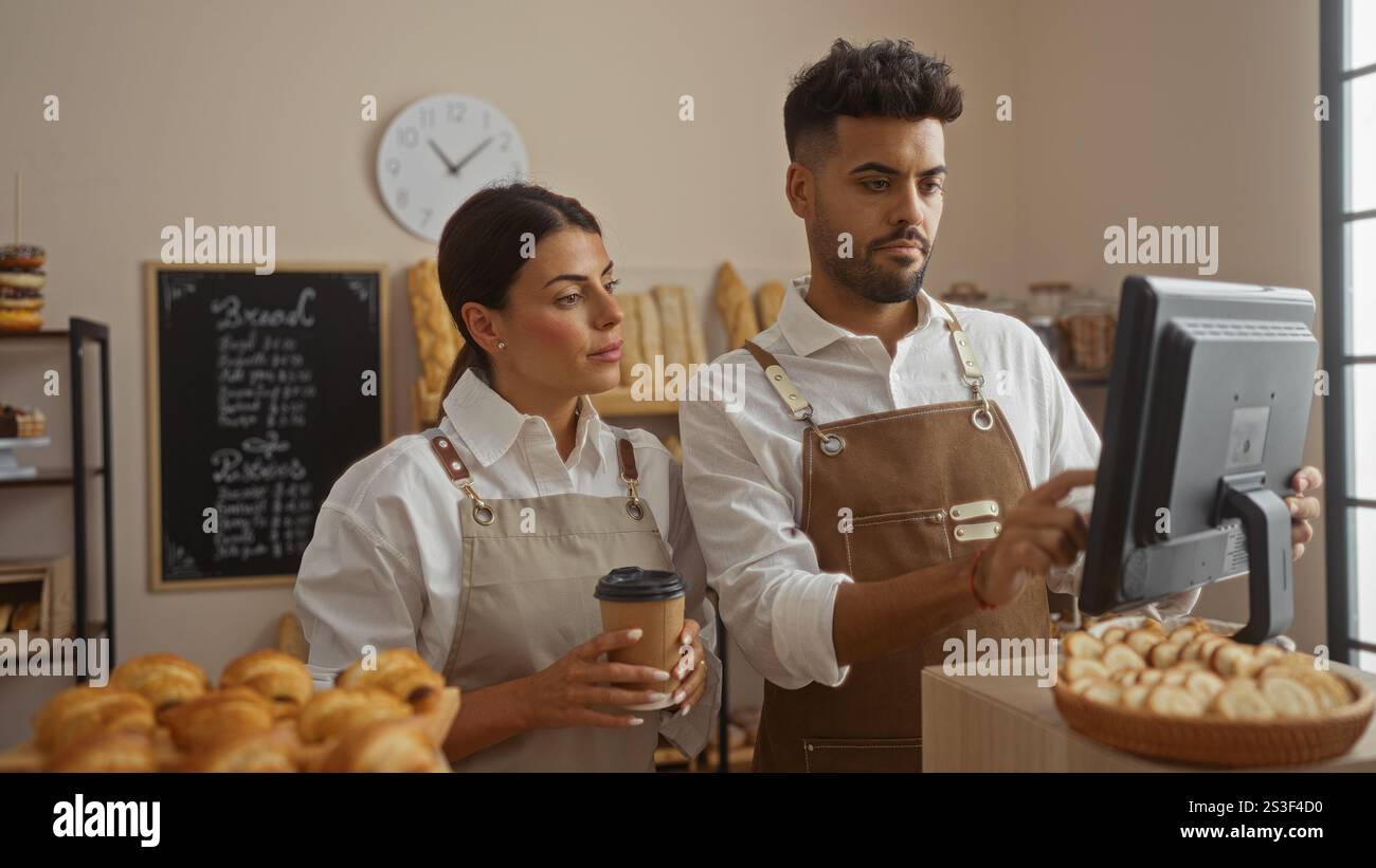 Man and woman using point of sale system in bakery shop with pastries ...