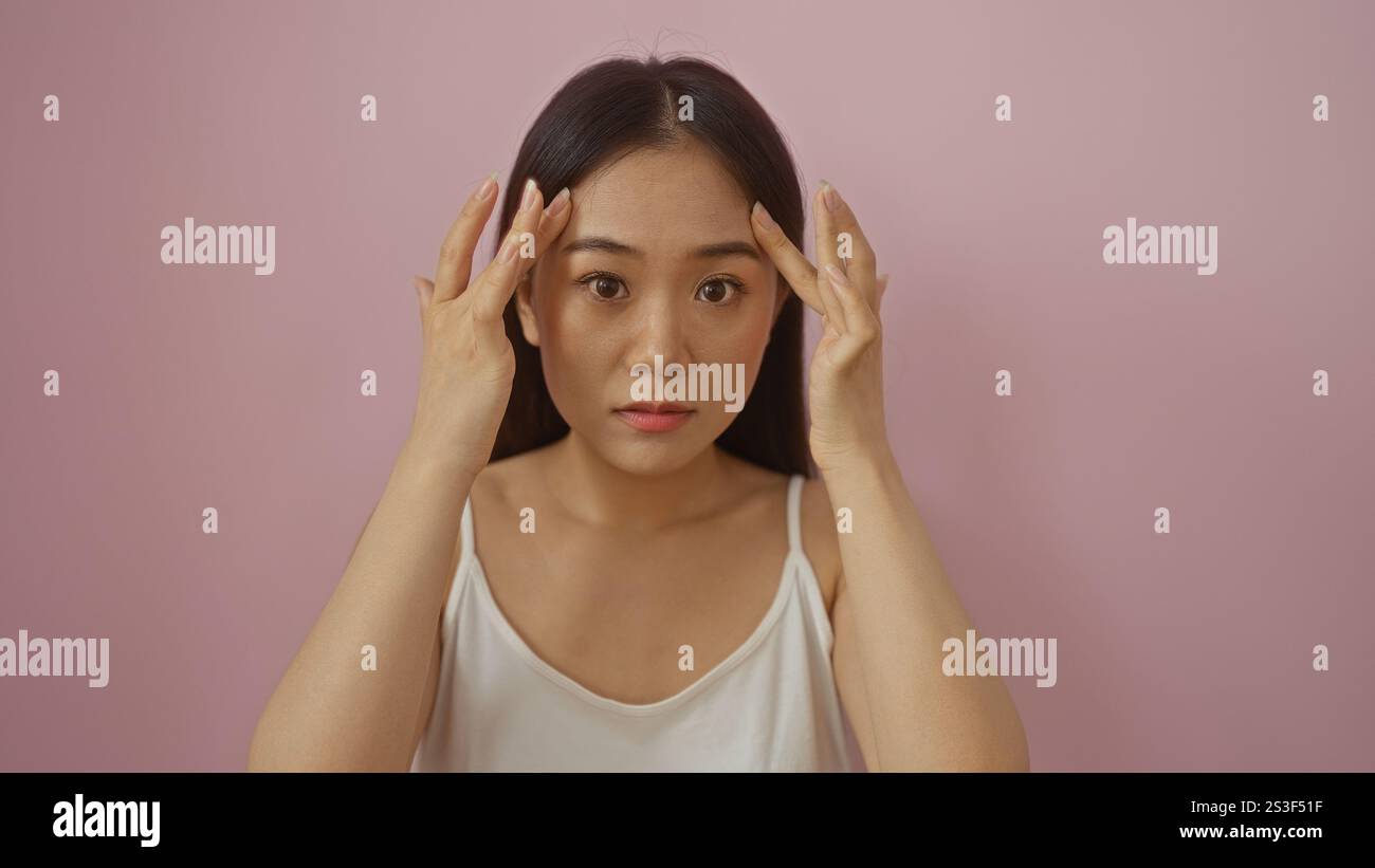 Beautiful young chinese woman isolated over a pink background touching ...