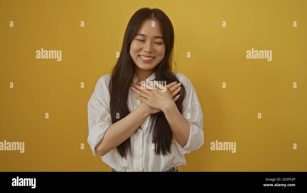 Woman smiling against isolated yellow wall with hands crossed over ...