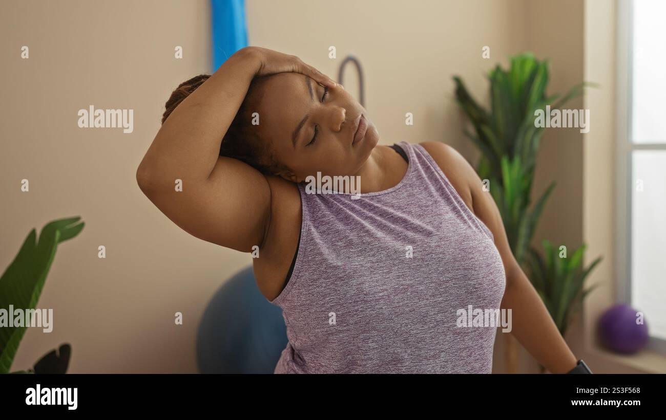 Woman stretching indoors at gym center, young african american adult ...