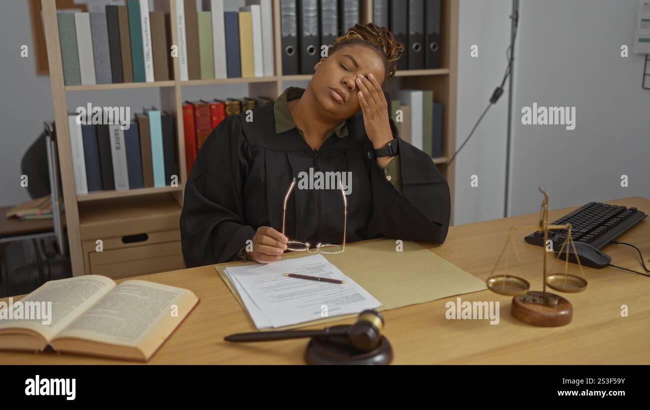 Woman judge sitting indoors in office rubbing forehead with scale of ...