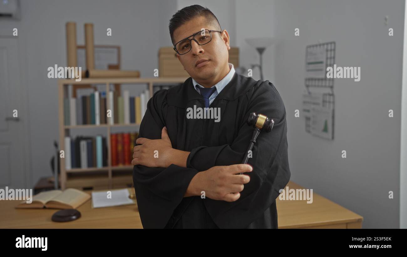 Confident young man in judge's robe, holding a gavel, standing with ...