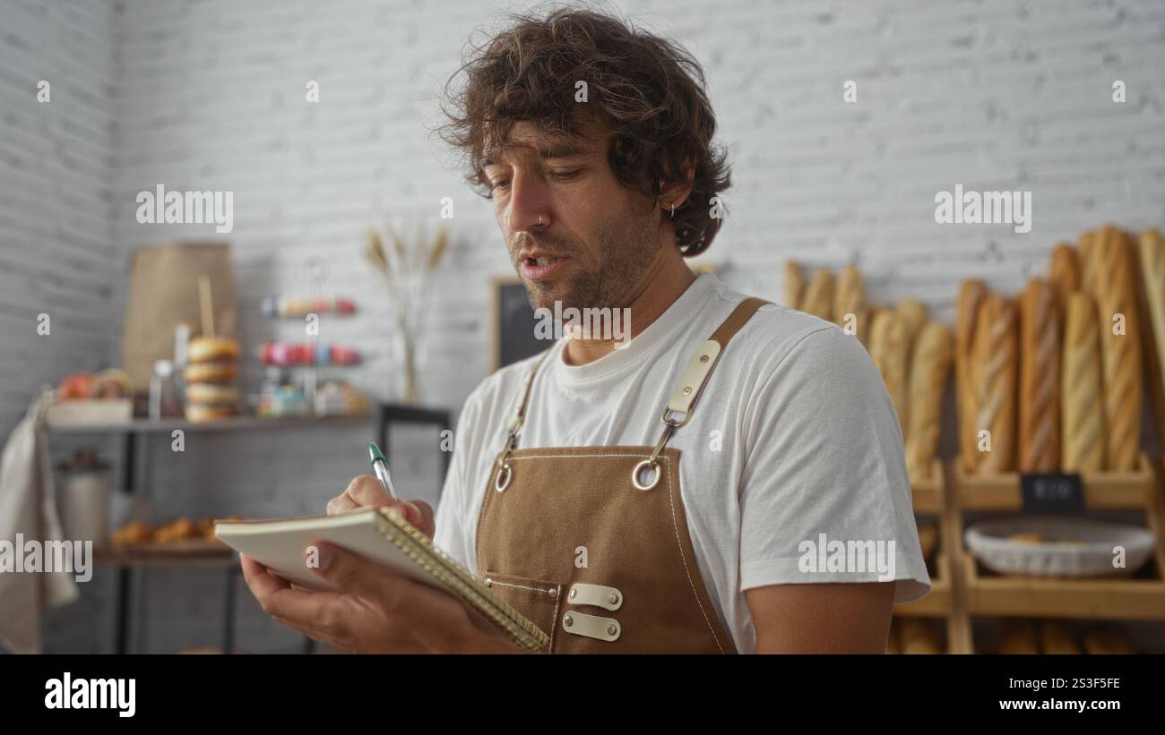 Young man writing notes in a bakery shop interior surrounded by bread ...