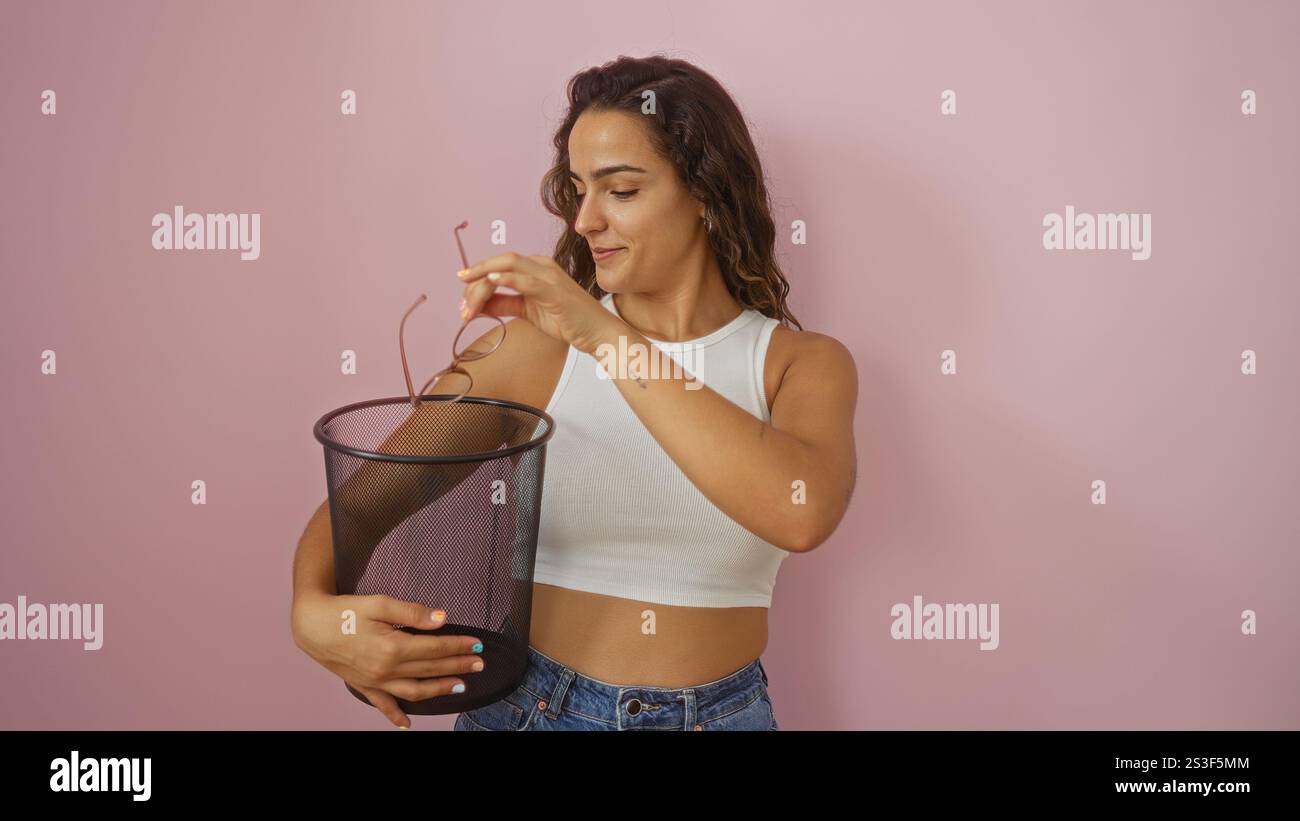 Woman discarding glasses in trash while standing against pink ...