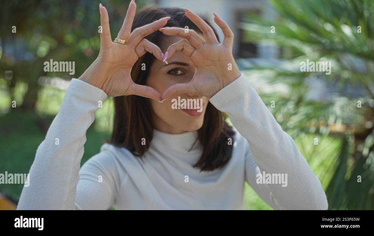 Woman forming heart shape with hands outdoors in a city park ...
