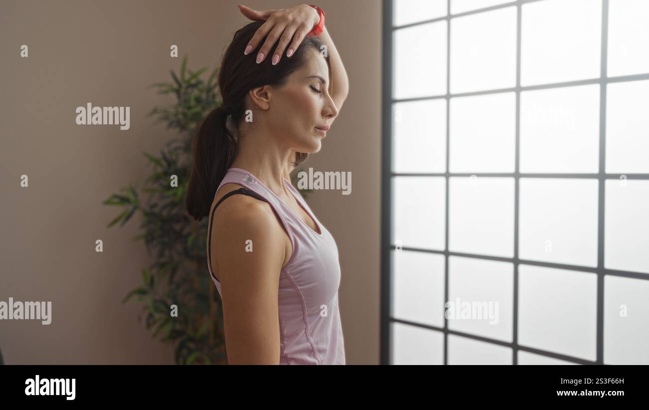 Woman stretching indoors at a gym with soft lighting and serene ...