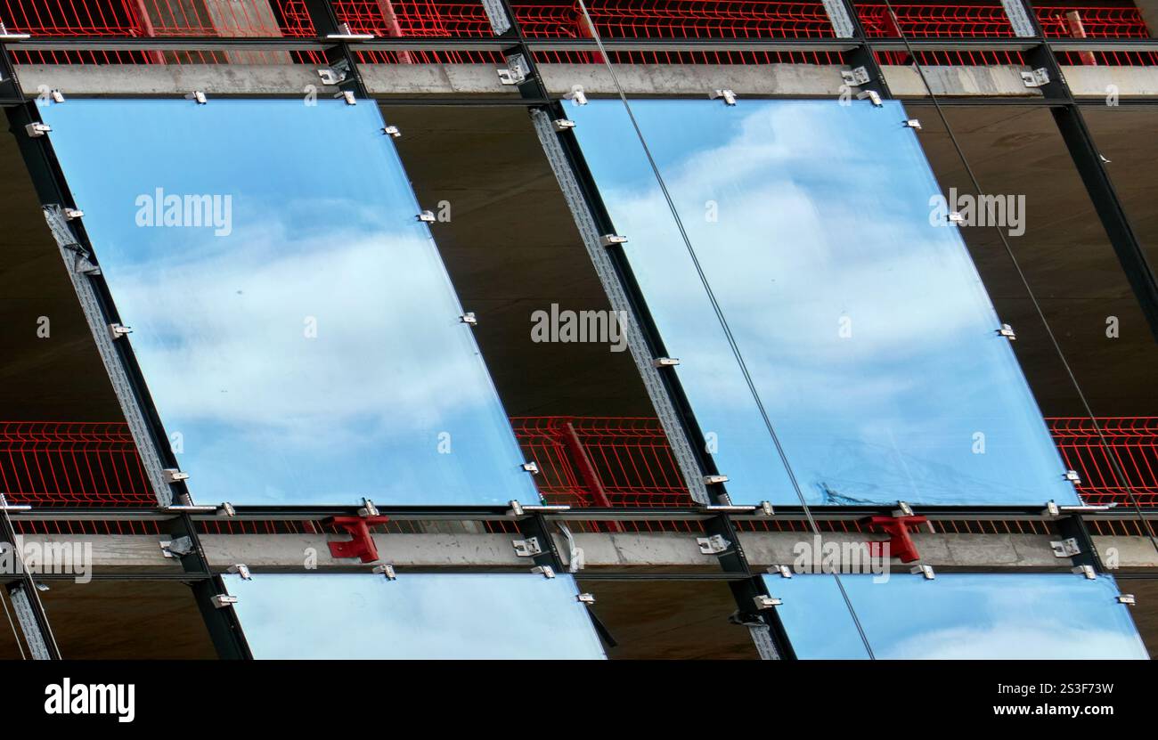 window panes in a building under construction with reflection of blue ...
