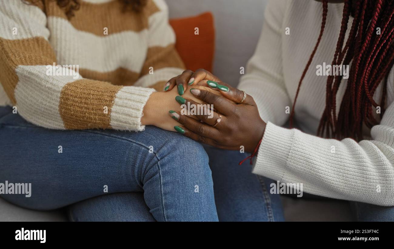Two women friends sitting together in an indoor living room sharing a ...
