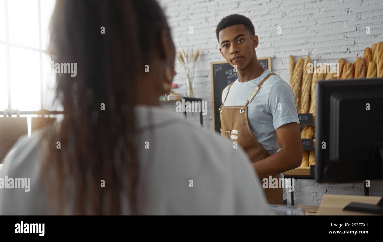 Man working behind counter in bakery shop interacting with woman ...