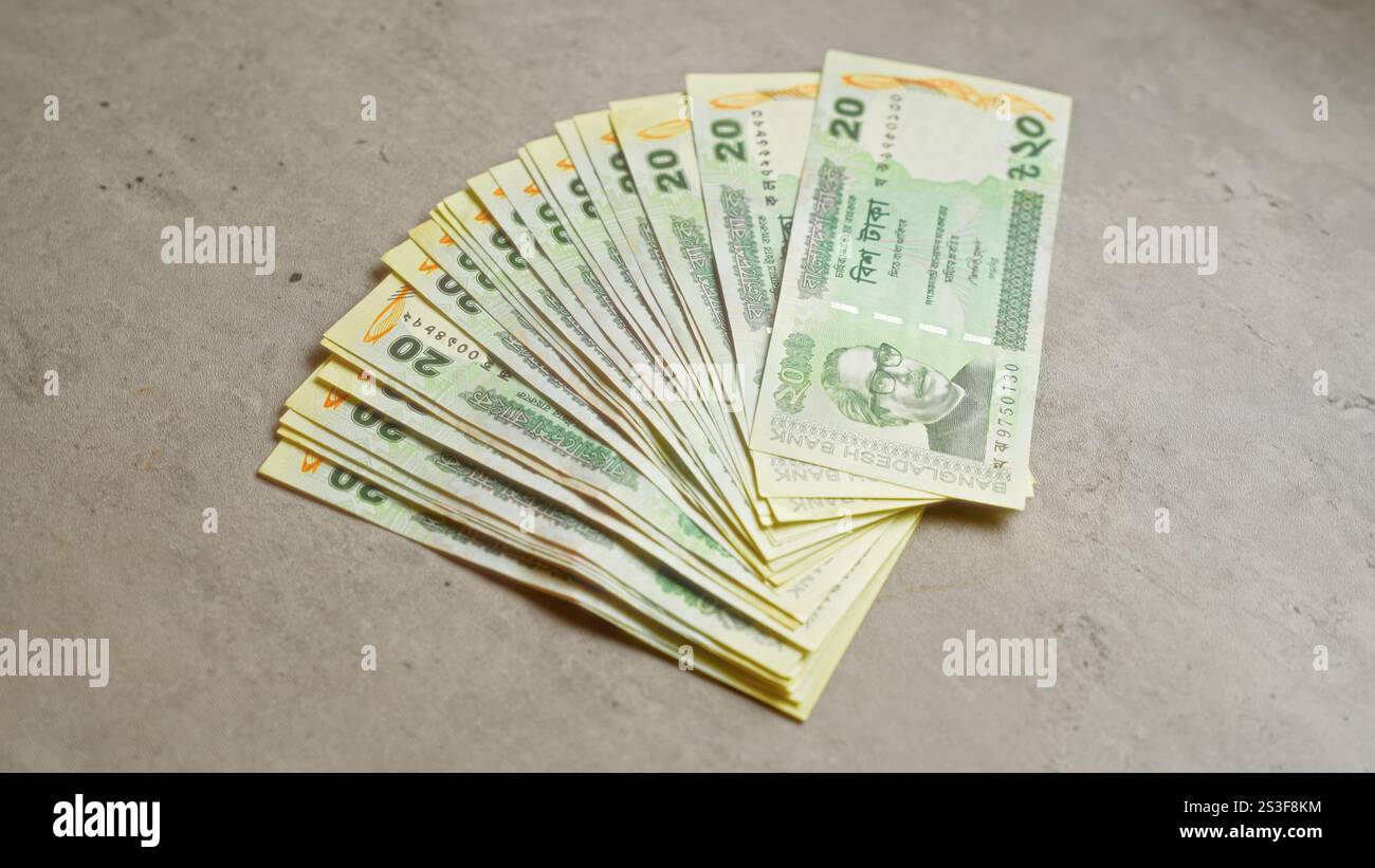Bangladeshi taka banknotes fanned out on a concrete surface, showcasing ...