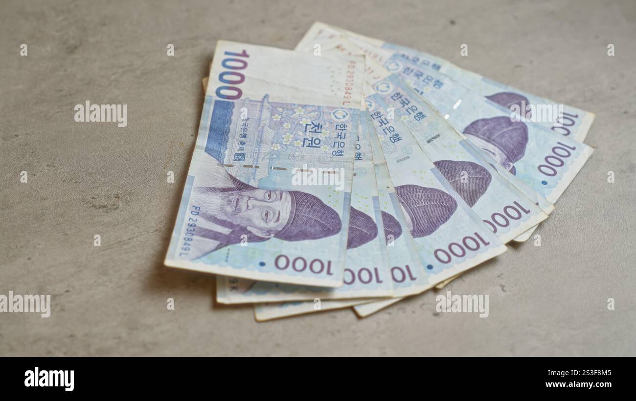 South korean banknotes spread out on a concrete surface, depicting the ...