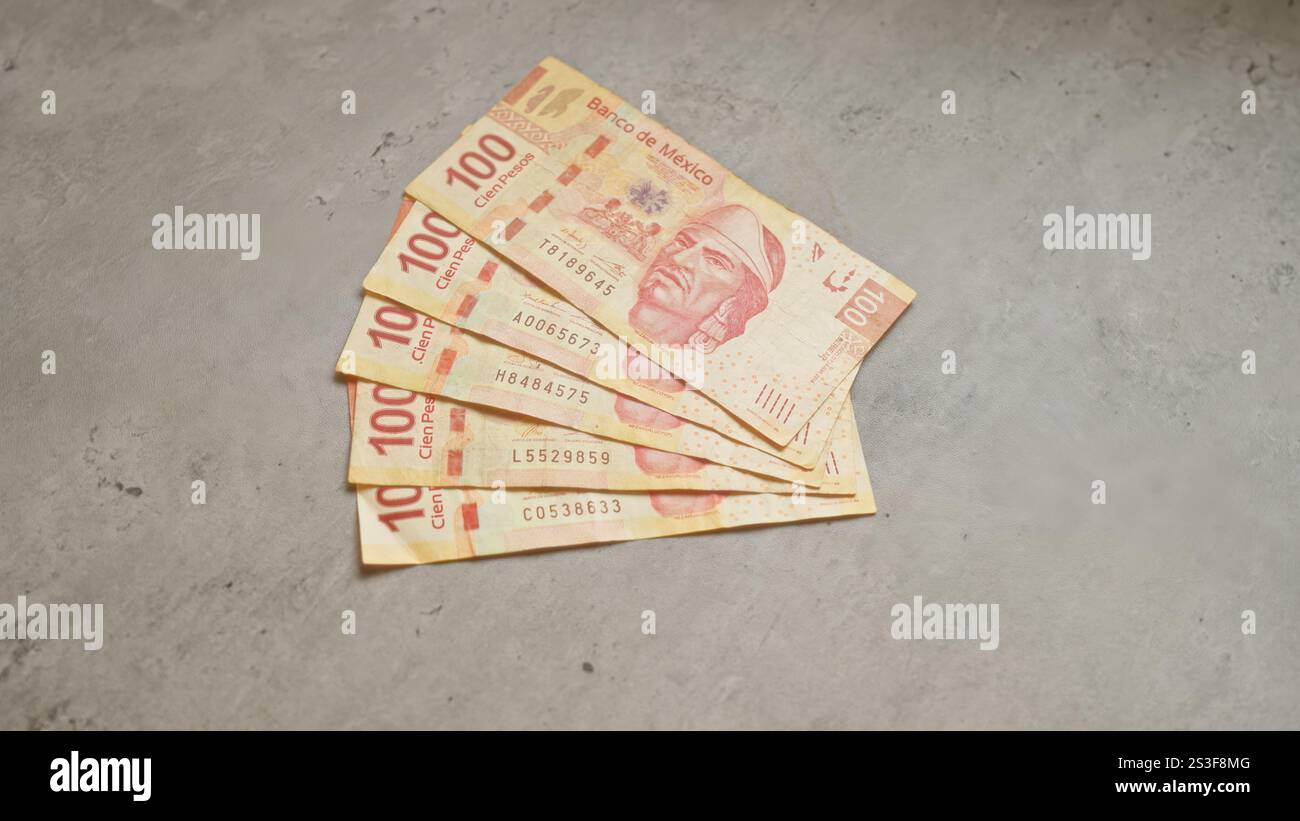 Mexican banknotes worth 100 pesos each are fanned out on a concrete ...