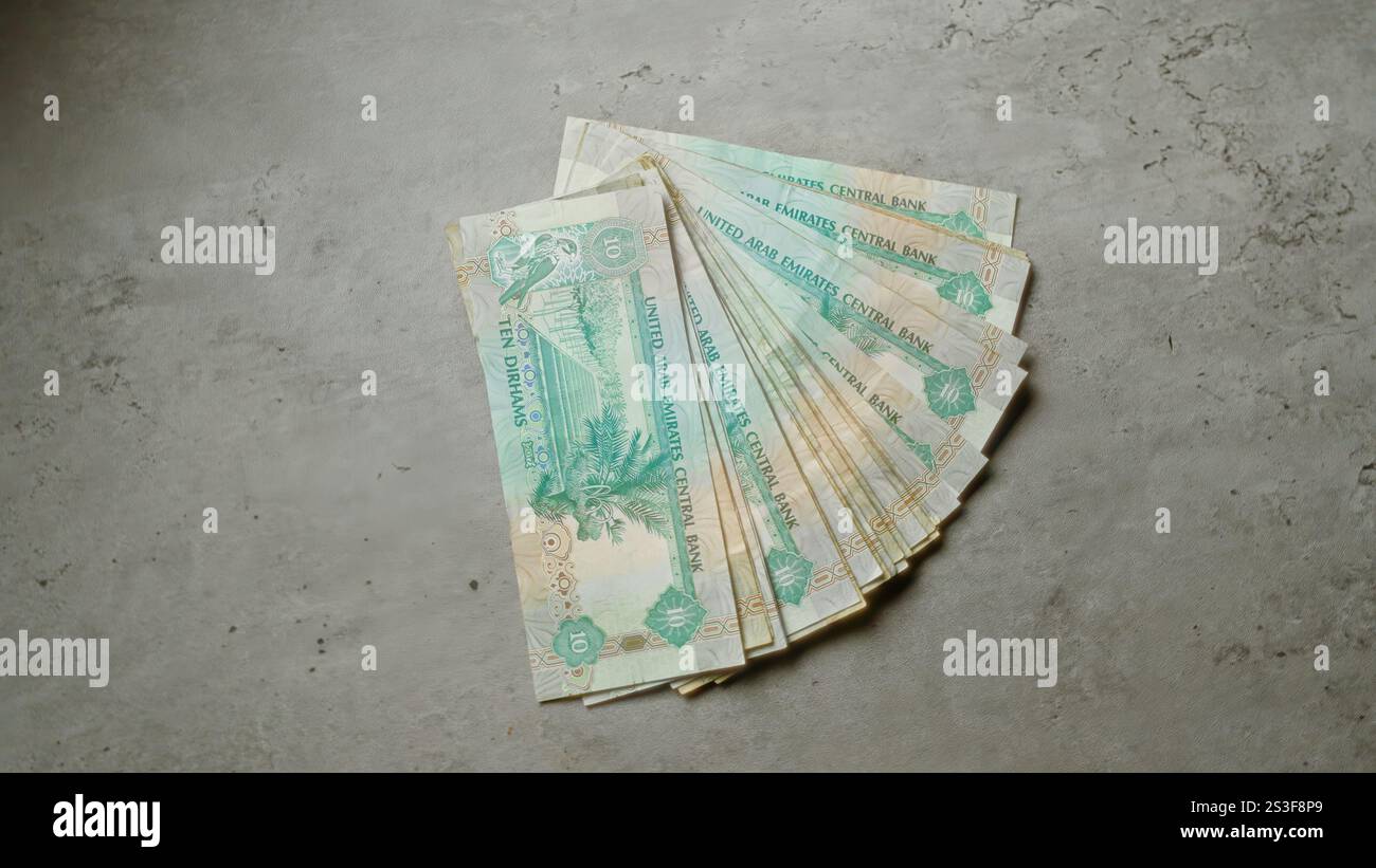 United arab emirates dirham banknotes spread out on a gray concrete ...