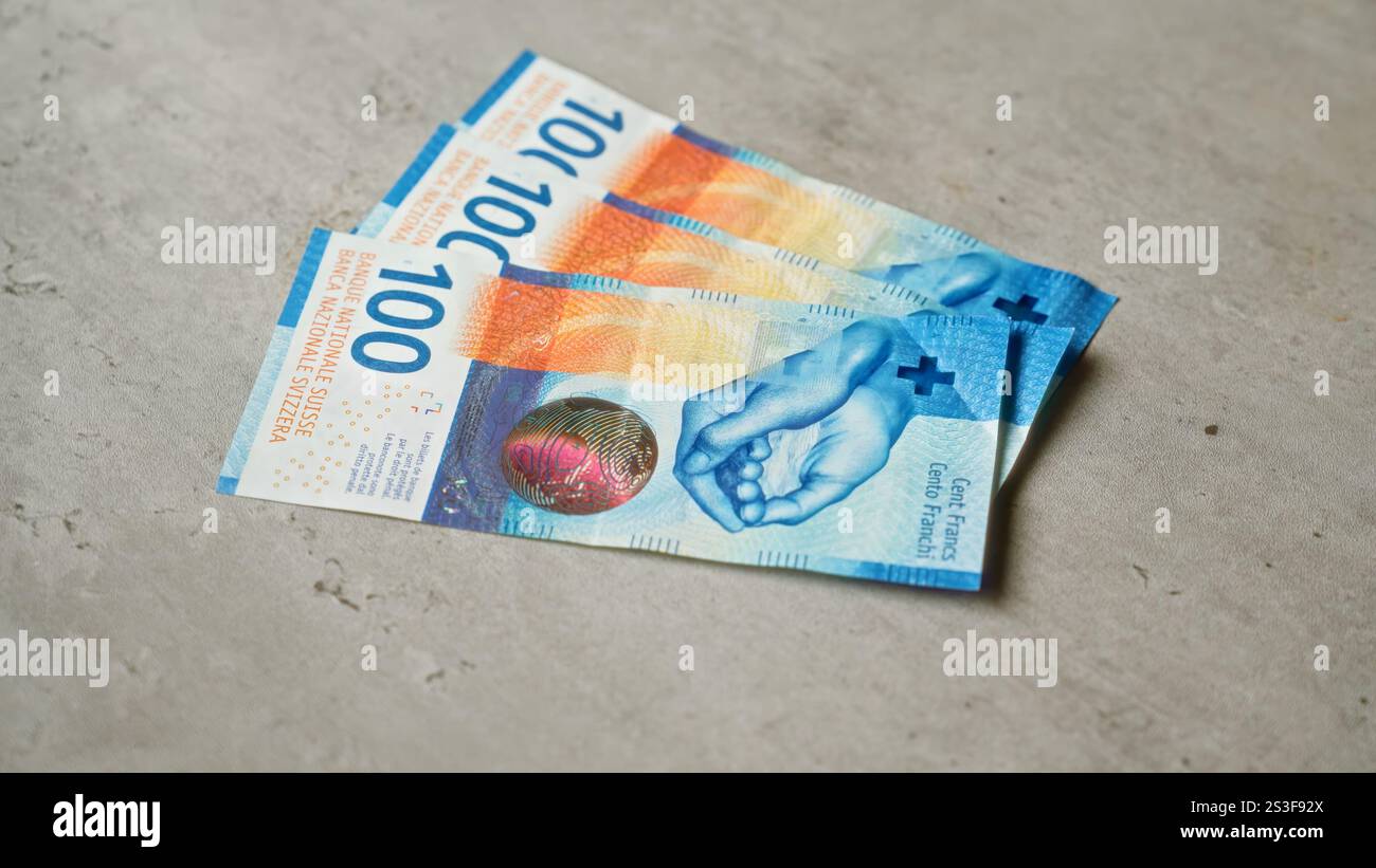 Swiss 100 franc banknotes are displayed on a concrete surface ...