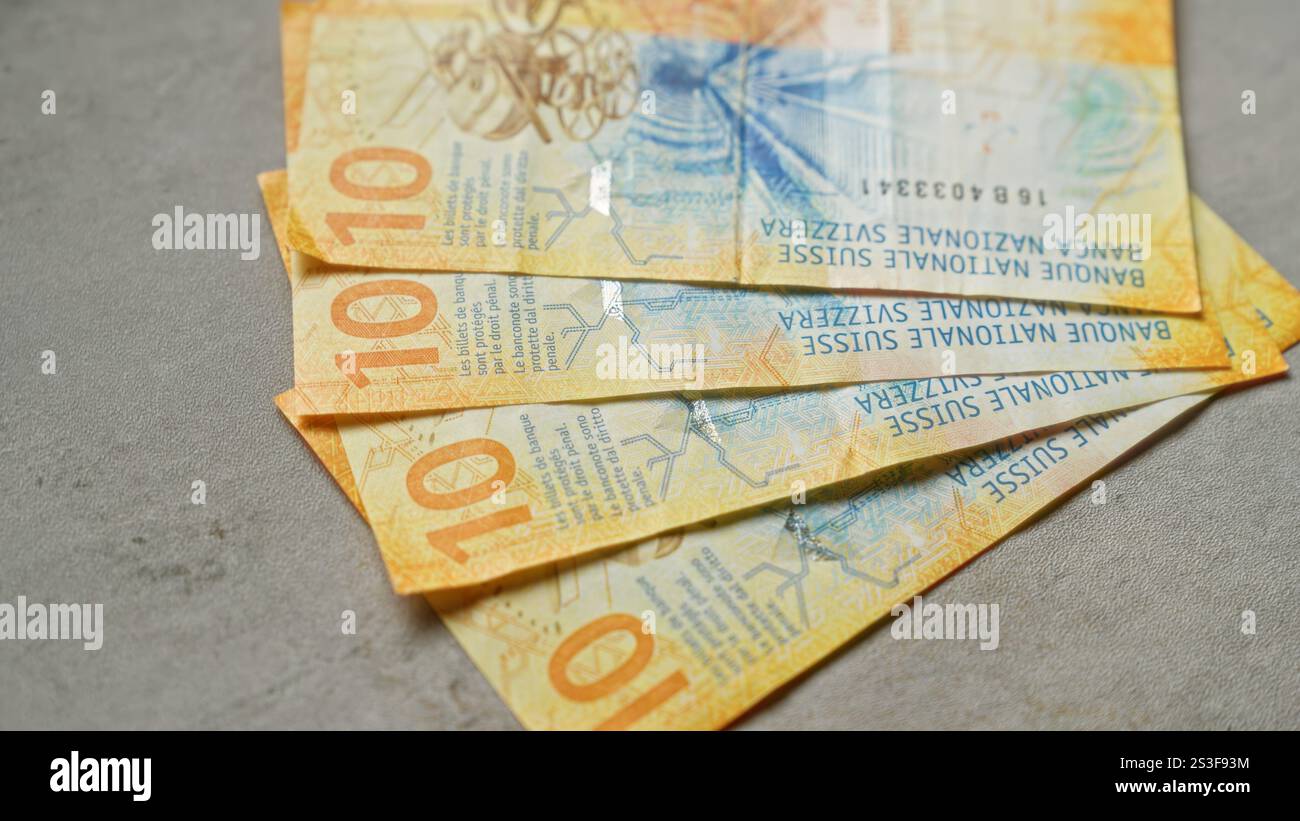 Swiss banknotes scattered on a concrete surface, highlighting colorful ...