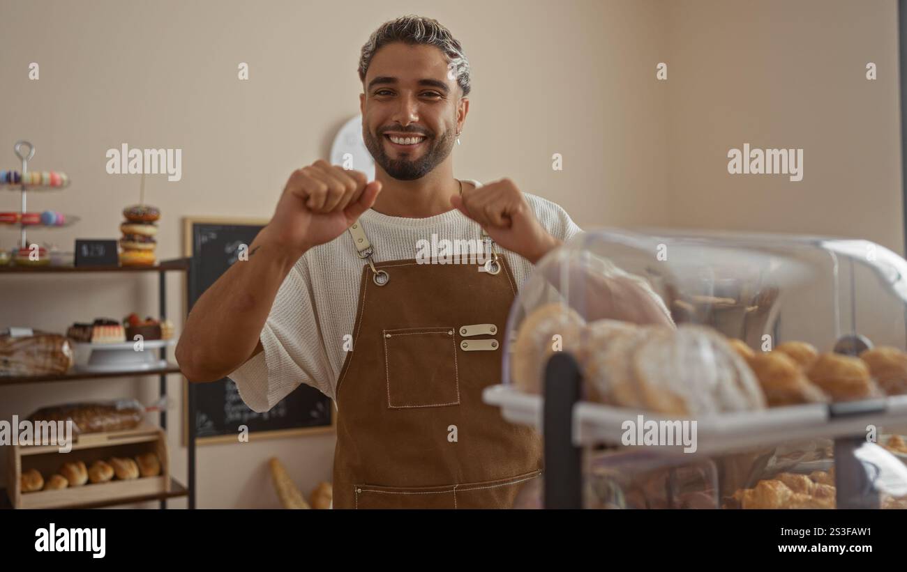 Young, arab, man smiling and celebrating in a cozy bakery shop interior ...