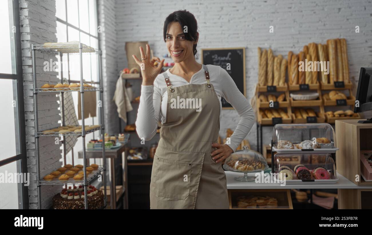 Hispanic woman standing in bakery shop wearing apron smiling and ...