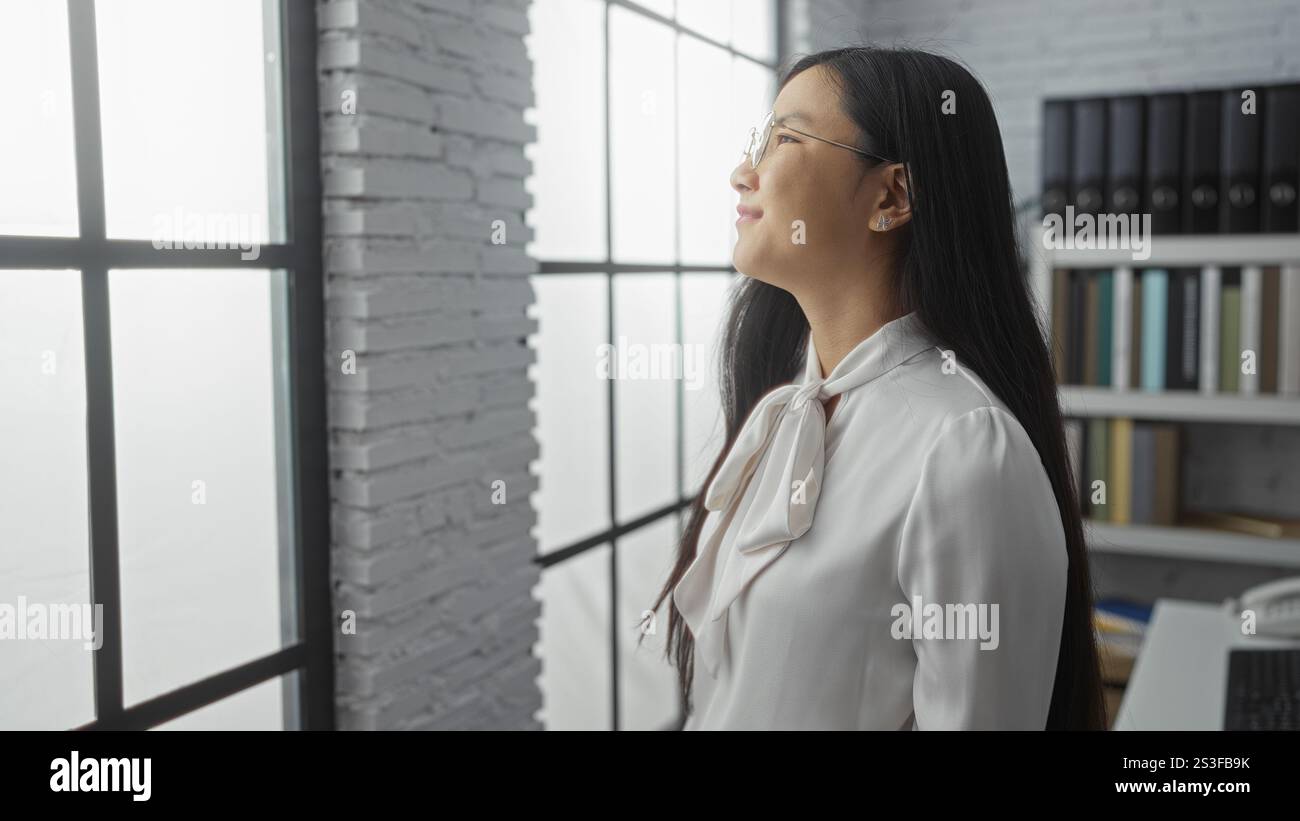 Woman smiling in modern bright office looking out window with white ...