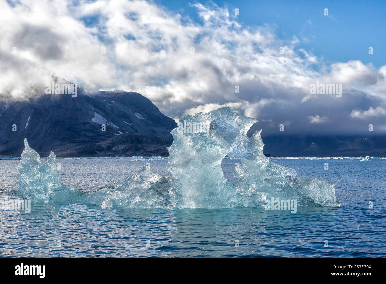A small melting iceberg with almost transparent ice floats in front of ...