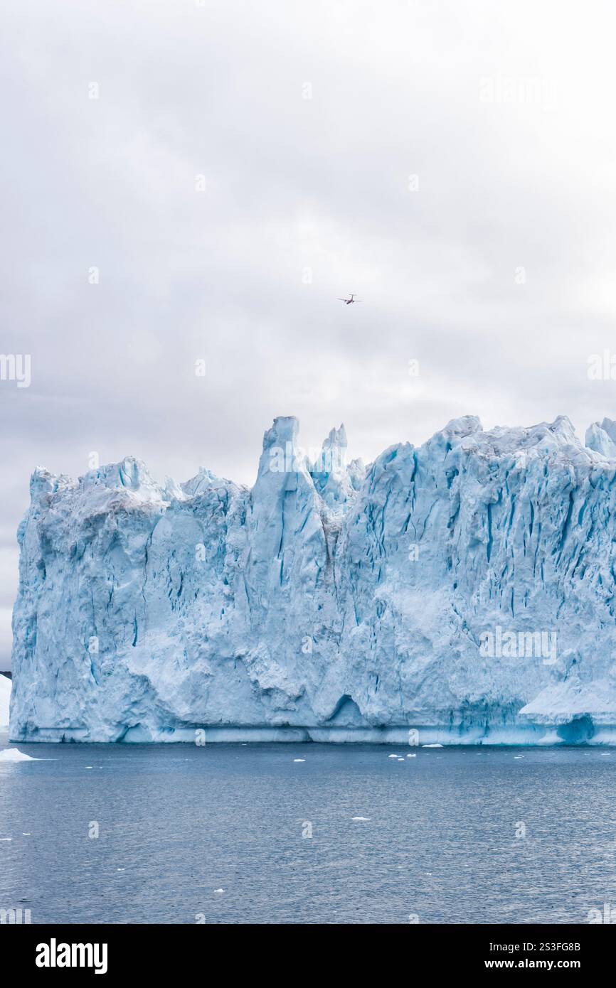 An Air Greenland airplane flies over a huge iceberg floating in the ...