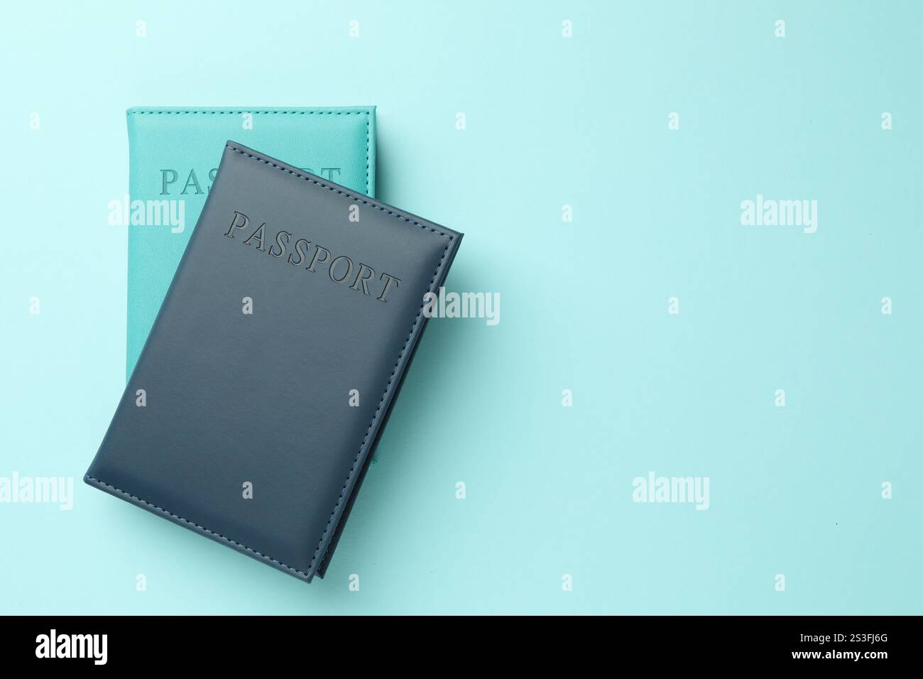 Passports in color covers on light blue background, top view. Space for ...