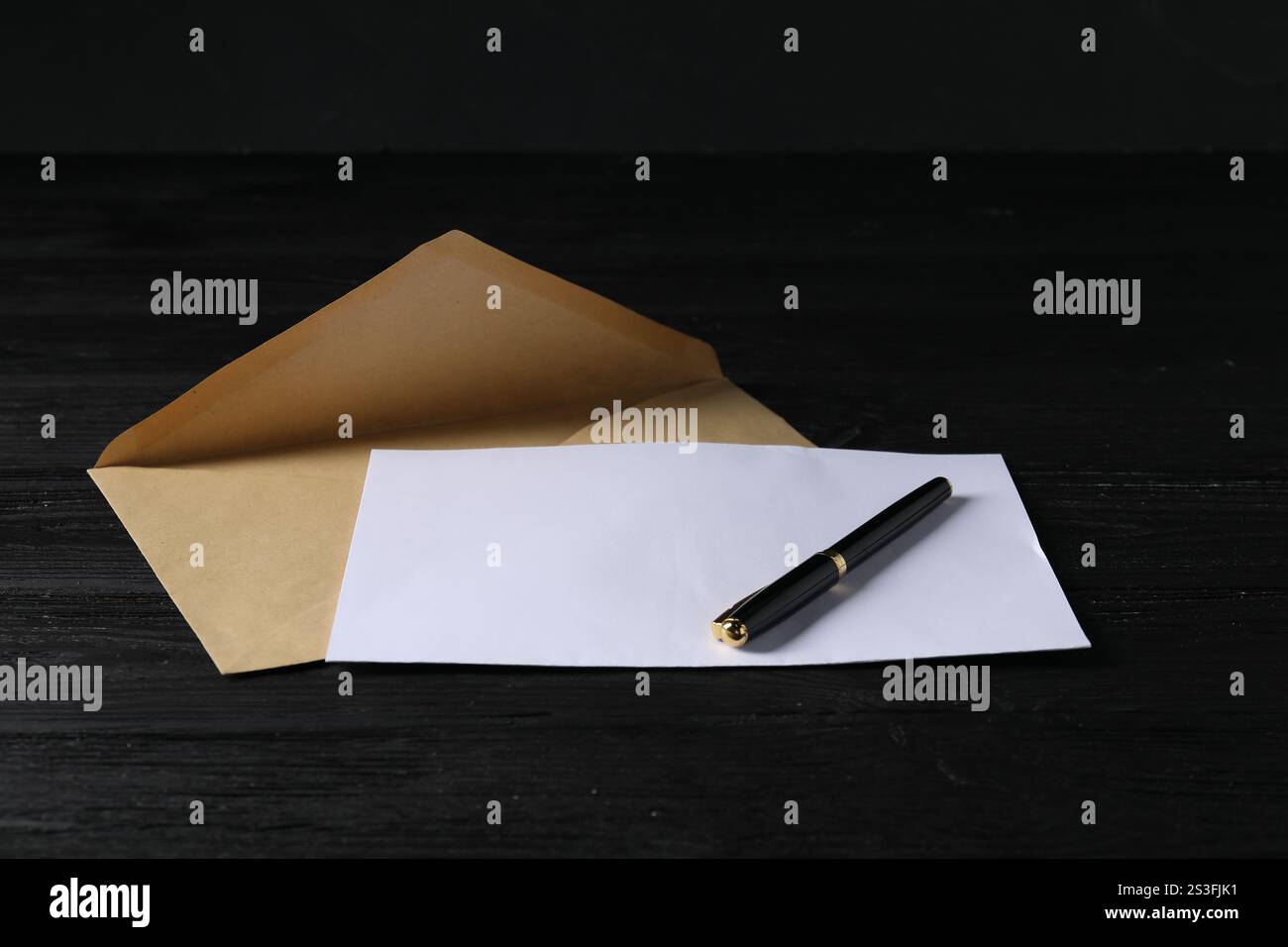 Kraft paper envelope with letter and pen on black wooden table. Mockup ...