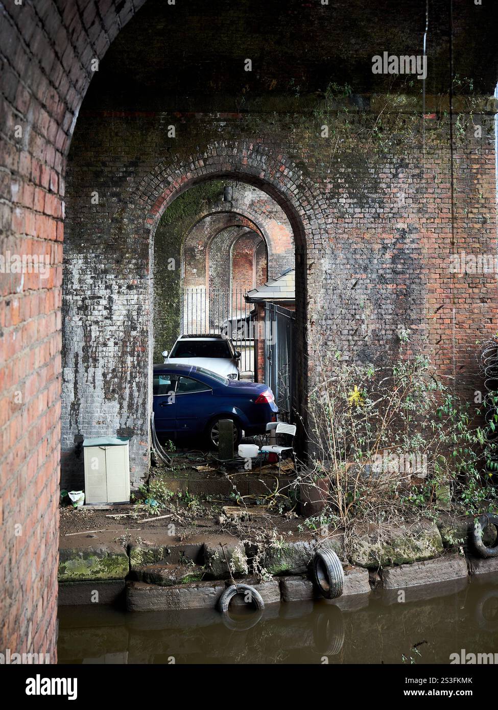 A car parked under a series of brick railway archways next to a leafy ...