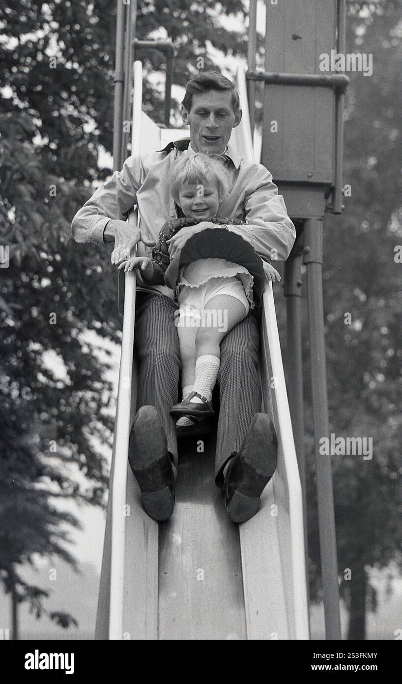 1970s, historical, a father with his young daughter on his lap going ...