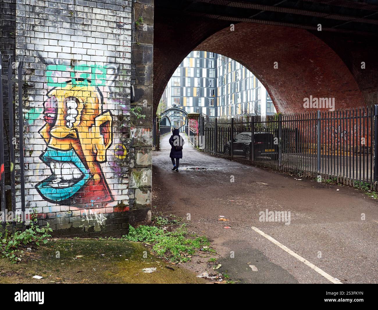 Manchester, UK, 01-04-2025: Urban graffiti under a brick archway with a ...
