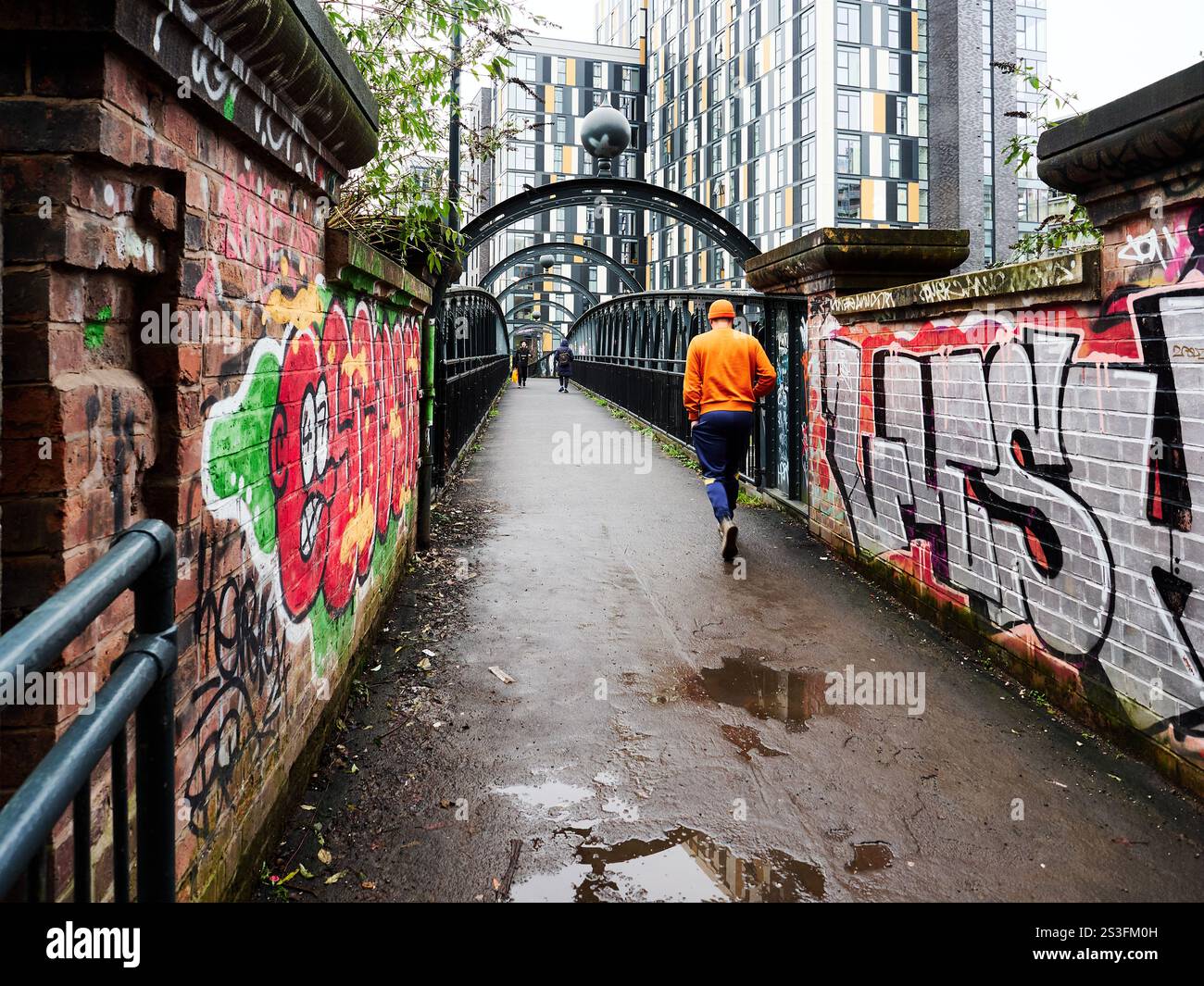 Manchester, UK, 01-04-2025: Person in orange running through graffiti ...