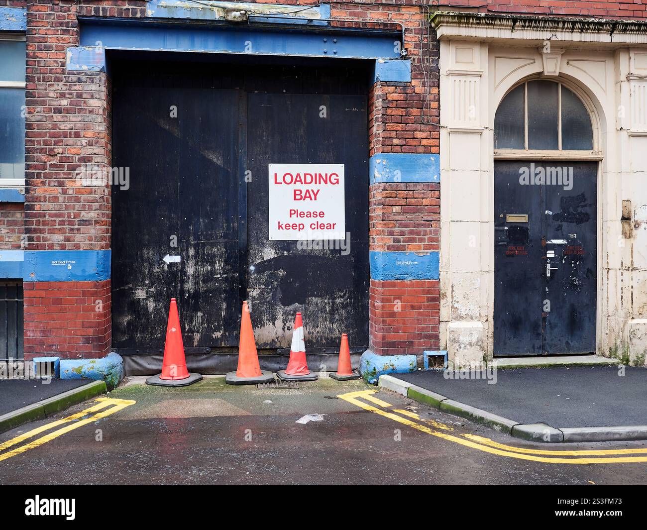 Brick building with loading bay sign and safety cones outside Stock ...
