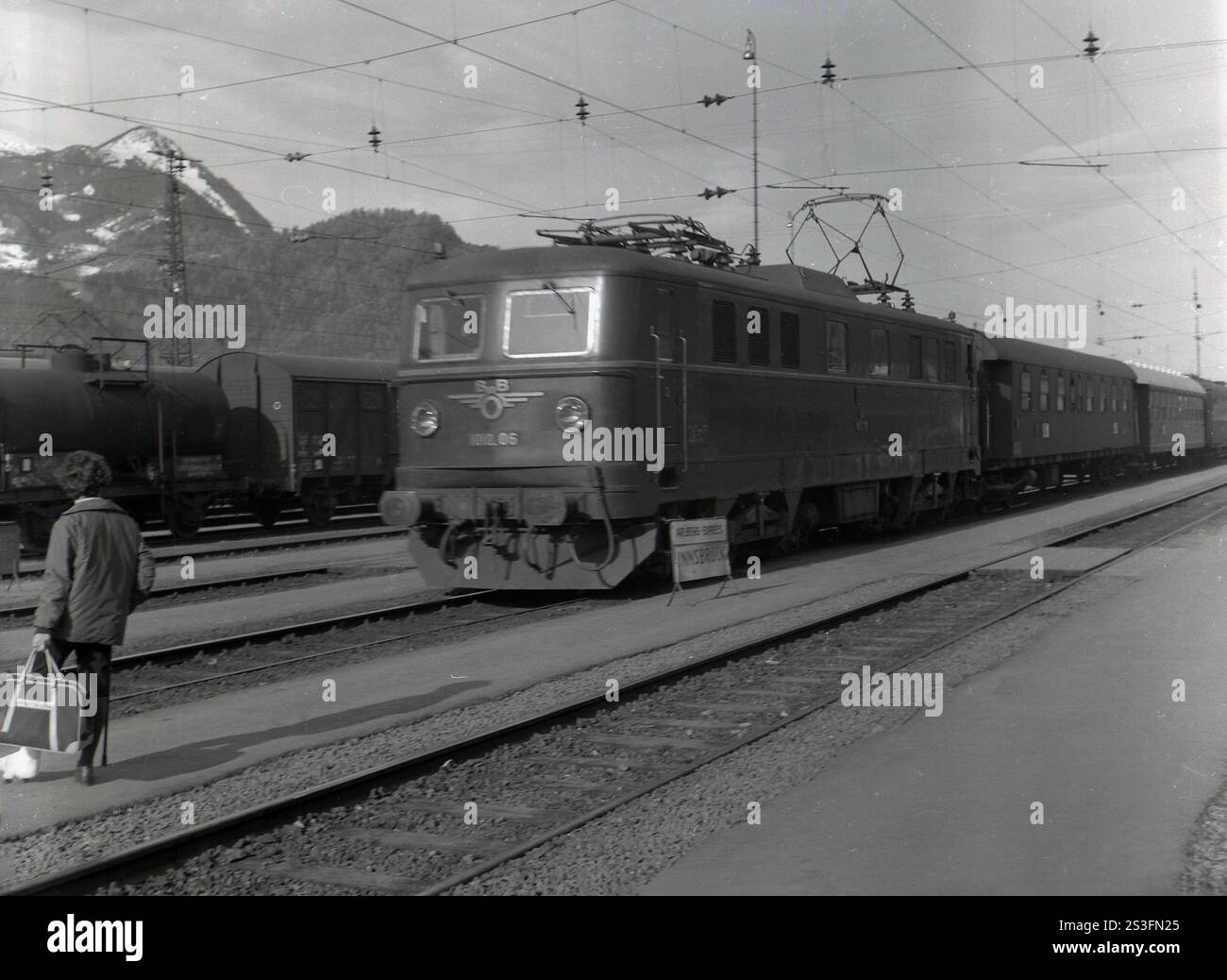 1960s, historical, a lady standing on a platform at a train station ...